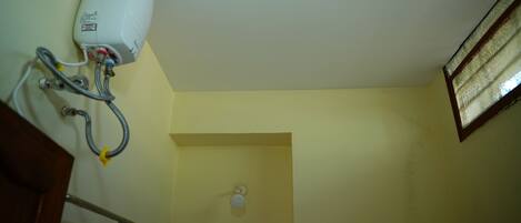 Casa de banho com secador de mãos, um porta-toalhas e chuveiro.