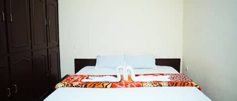 Quarto de hotel com cama, guarda-roupa e ar condicionado fixado na parede.