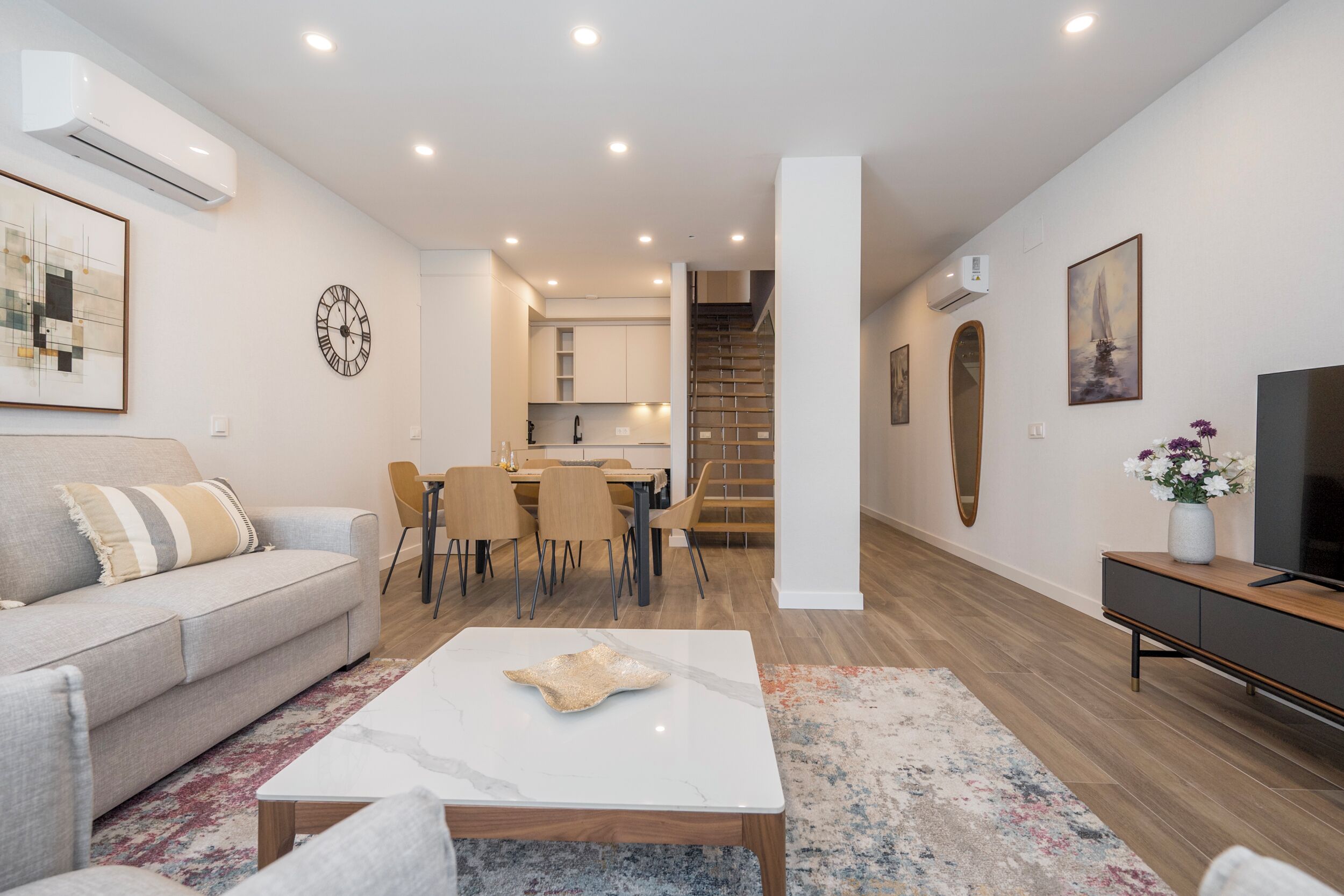 Uma sala de estar moderna com sofá, mesa de centro e aparador para TV.