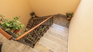 Uma escadaria com corrimão de madeira, plantas em vasos e piso de pedra.
