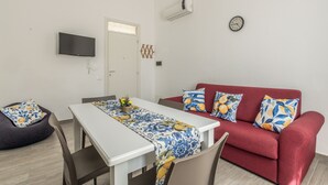 Uma sala de estar moderna com uma mesa branca, sofá vermelho e TV na parede.