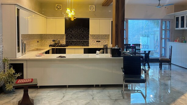 Cozinha moderna com ilha central, iluminação pendente e vista para o exterior.