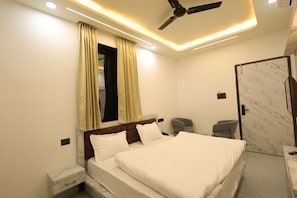 Quarto com cama, ventilador de teto, mesa de cabeceira, escrivaninha e porta com padrão marmorizado.