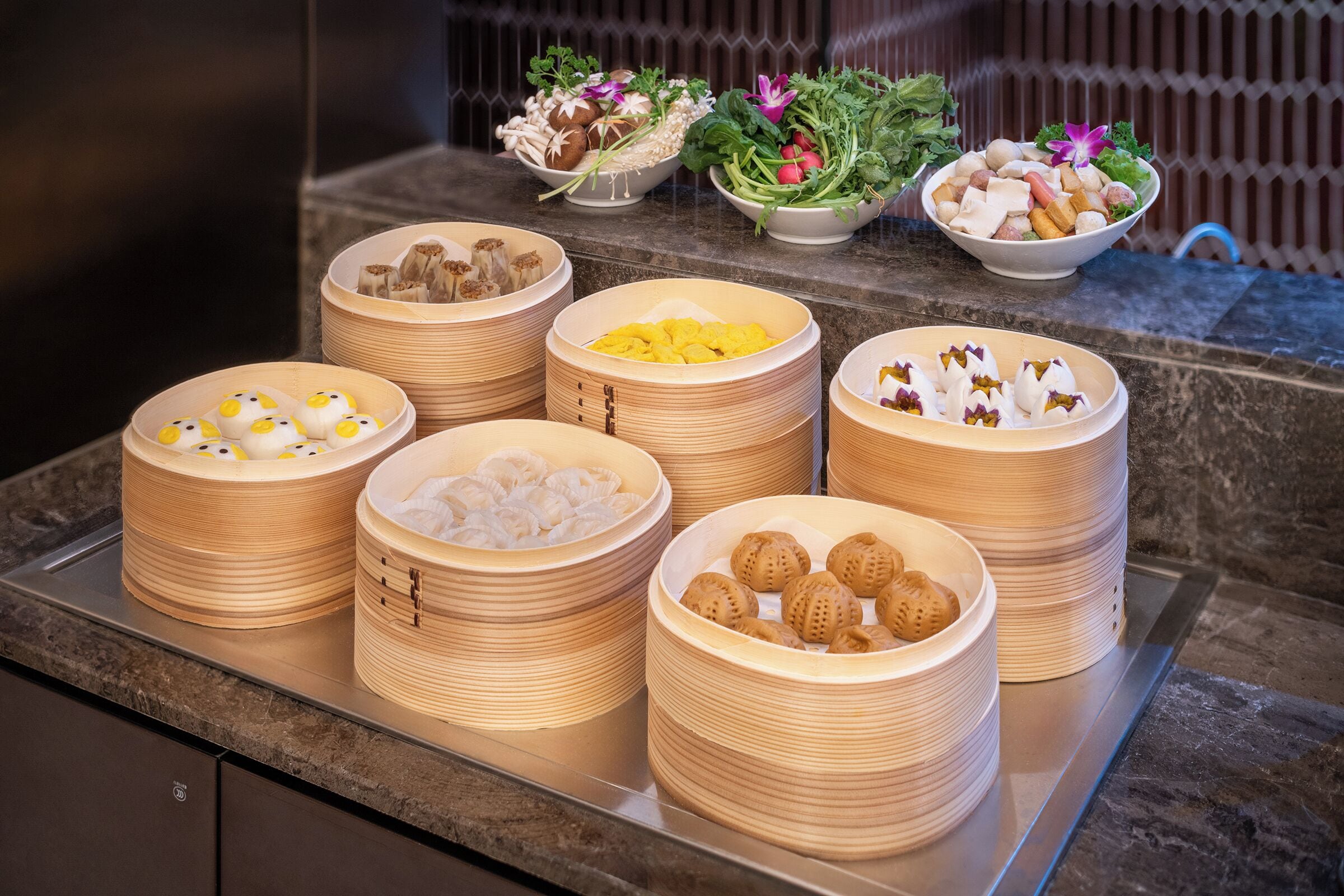 Buffet com diversos alimentos em cestas de bambu.