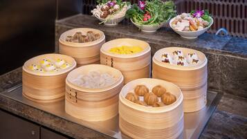 Buffet com diversos alimentos em cestas de bambu.