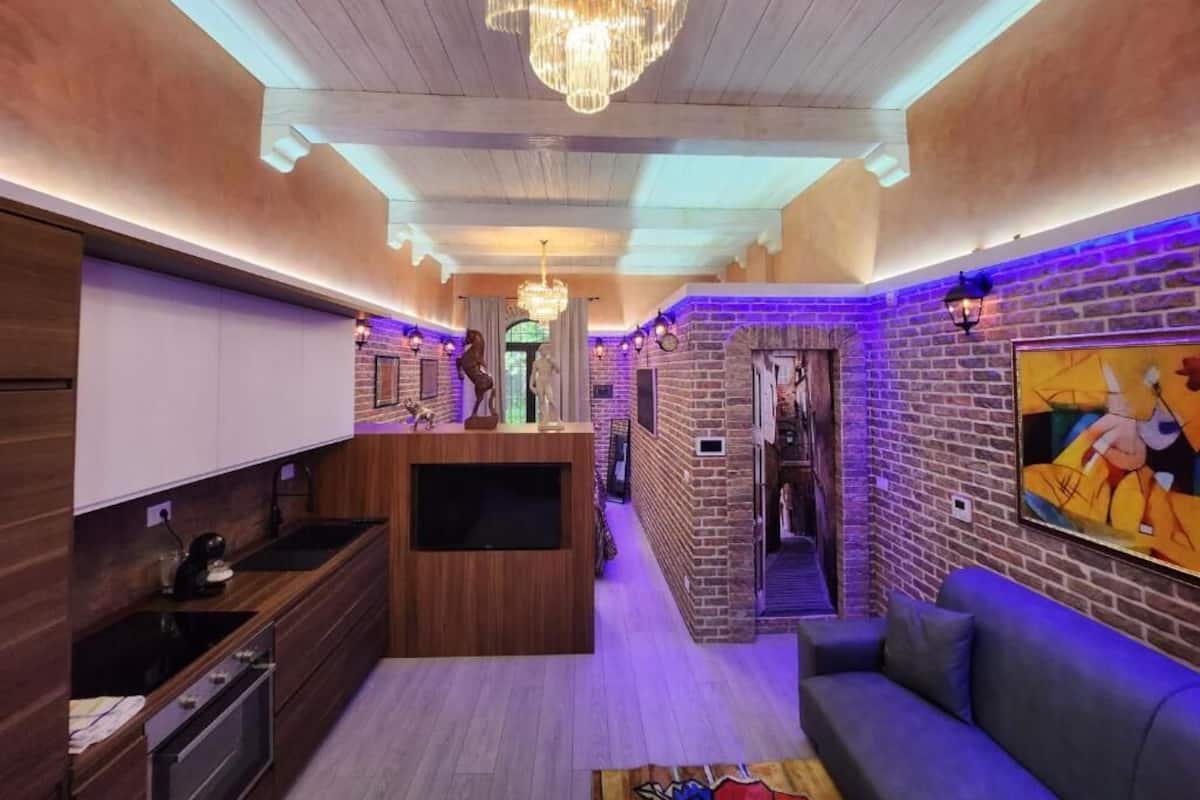 Interior moderno com cozinha, área de estar e corredor com paredes de tijolo e um candelabro.