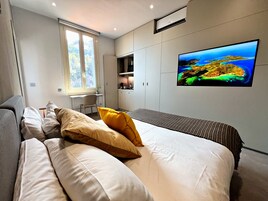 Um quarto moderno com uma cama, uma escrivaninha e uma TV fixada na parede.