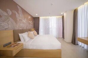 Quarto de hotel moderno com uma cama grande, uma mesa de cabeceira, uma TV na parede e uma janela com cortinas.