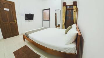 Quarto com cama de madeira, TV de tela plana, janela com cortinas e aparelho de ar condicionado.