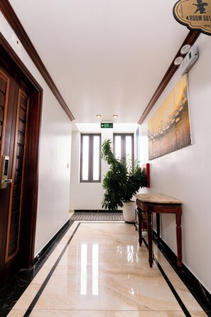 Um corredor de hotel com porta de madeira, planta em vaso, quadro e placa indicando 'Room 601'.