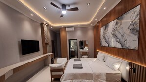 Quarto moderno com uma cama grande, uma TV, um ventilador de teto e uma obra de arte de mármore na parede.