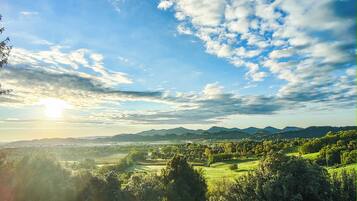 Vista de um terraço com telhado de cerâmica, sobre um panorama verde com árvores e colinas ao longe.