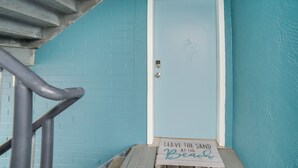 Uma porta com uma placa que diz 'Deixe a areia na Praia'.