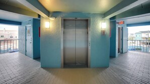 Um elevador em um edifício com paredes azuis e chão de azulejos.