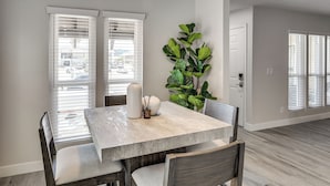 Uma área de refeições com mesa, cadeiras, ventilador de teto e uma planta grande.