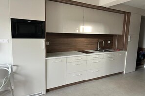 Cozinha moderna com armários brancos, micro-ondas e pia.