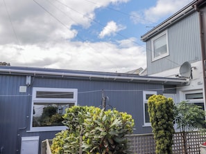Um edifício residencial com fachada cinza, janelas brancas e antena parabólica.