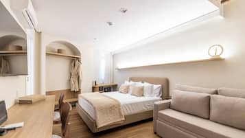 Quarto de hotel moderno com cama, sofá, escrivaninha e guarda-roupa.