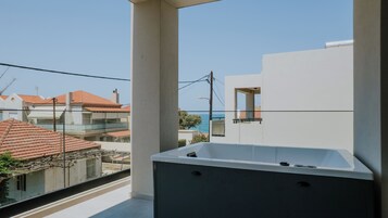 Uma varanda com hidromassagem, com vista para uma área residencial com telhados vermelhos e um céu azul límpido.