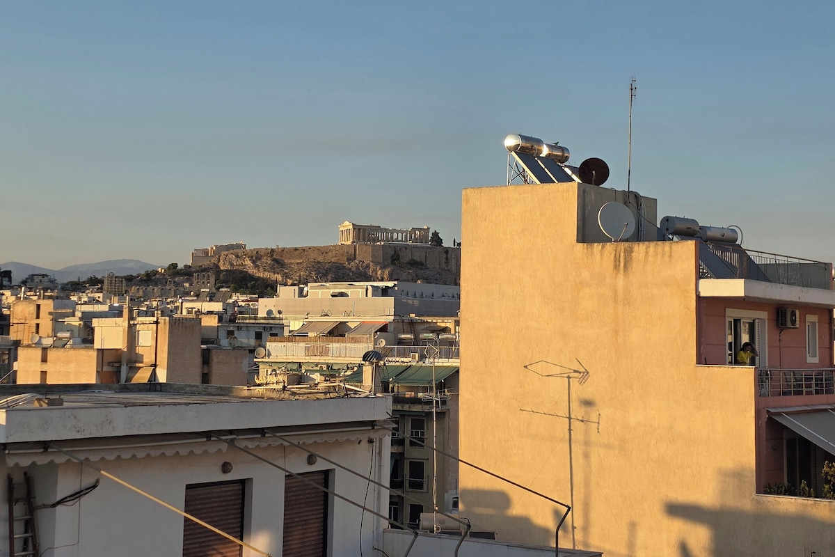 Terraço com antenas parabólicas, uma escada e vista para um horizonte urbano com edifícios históricos.
