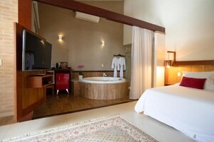 Quarto de hotel com cama, televisão, banheiro com banheira e um armário vermelho.