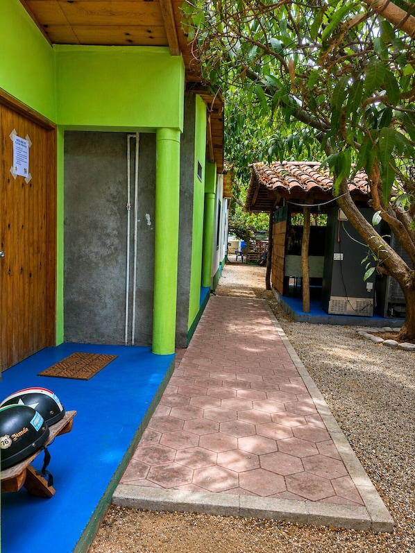 Uma passagem leva a um edifício com fachada verde e tapete azul no chão.