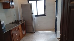 Uma cozinha compacta com geladeira, armários e janela.