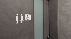Um sanitário com sinalização para banheiro masculino e feminino, e símbolo de acesso para pessoas com deficiência.