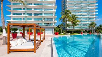 Um hotel moderno com piscina, área de estar externa e palmeiras.