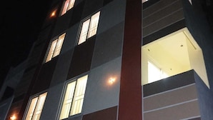 Um edifício com vários andares, janelas iluminadas e entrada visível.