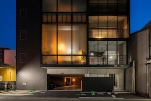 Um edifício moderno com grandes janelas, entrada coberta e escadaria visível.