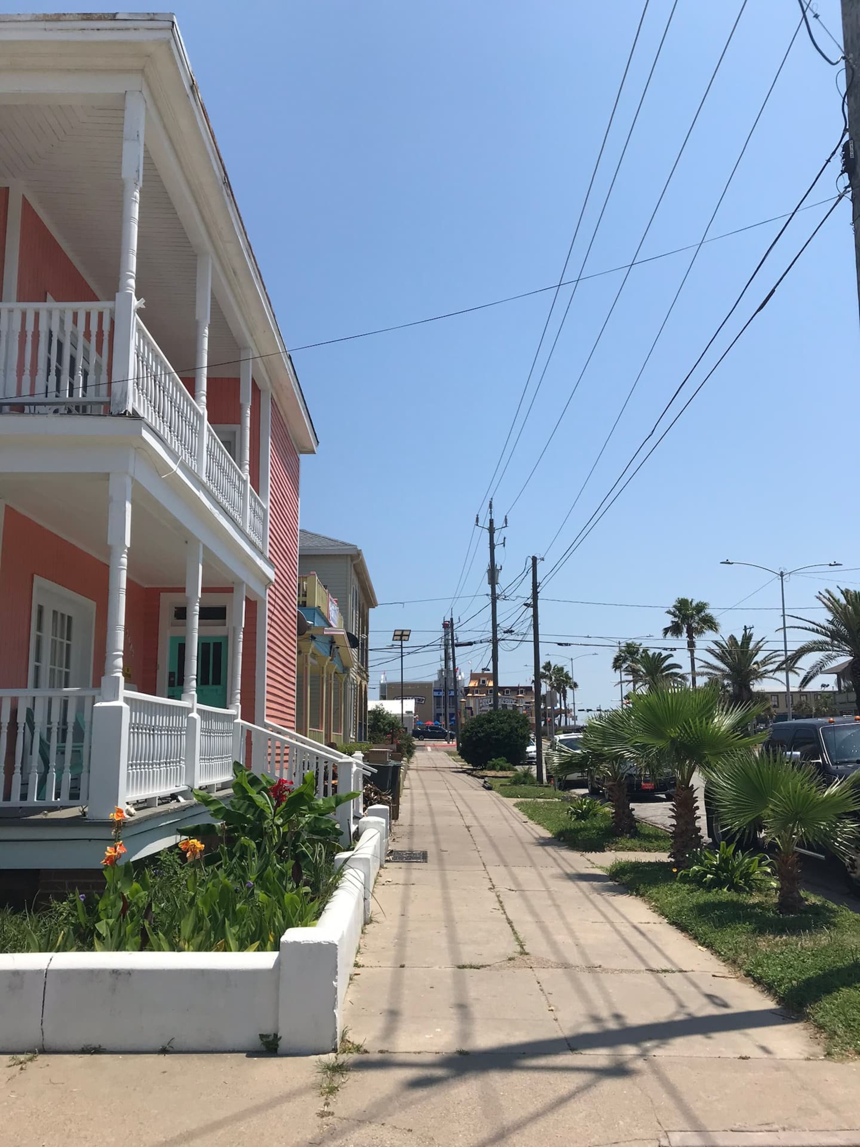 Rua residencial com casas, calçada e fios de eletricidade.