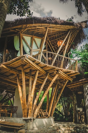 Estrutura de bambu com varanda, rodeada por vegetação.