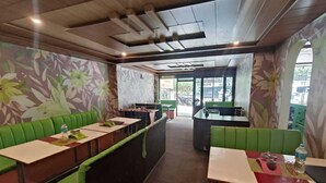 Um restaurante com cabines e mesas, arte floral nas paredes e vista para a rua.
