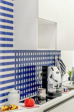 Cozinha com cafeteira, uma maçã vermelha e um painel de fundo xadrez.