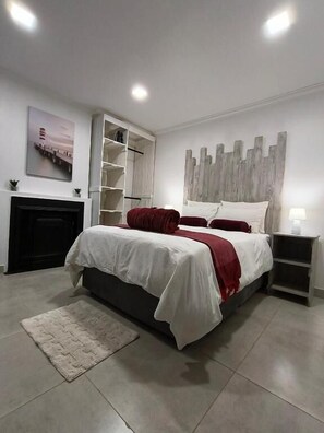 Quarto com cama, guarda-roupa, lareira e prateleira na parede.