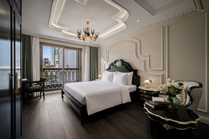 Quarto de hotel com cama grande, um candelabro, vista pela janela e varanda.