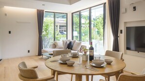 Uma sala de jantar moderna com mesa redonda, cadeiras de madeira e uma janela ampla com vista para o verde.