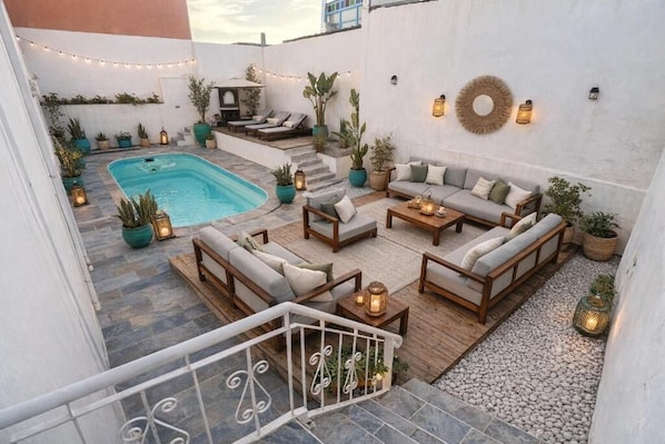 Um terraço no telhado com piscina, área de estar ao ar livre e luzes de corda.