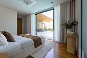 Quarto moderno com uma cama grande, vista para uma piscina ao ar livre e um vaso de planta.