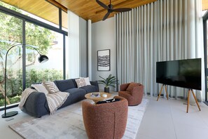 Uma sala de estar moderna com sofá, mesa de centro e televisão sobre um móvel.