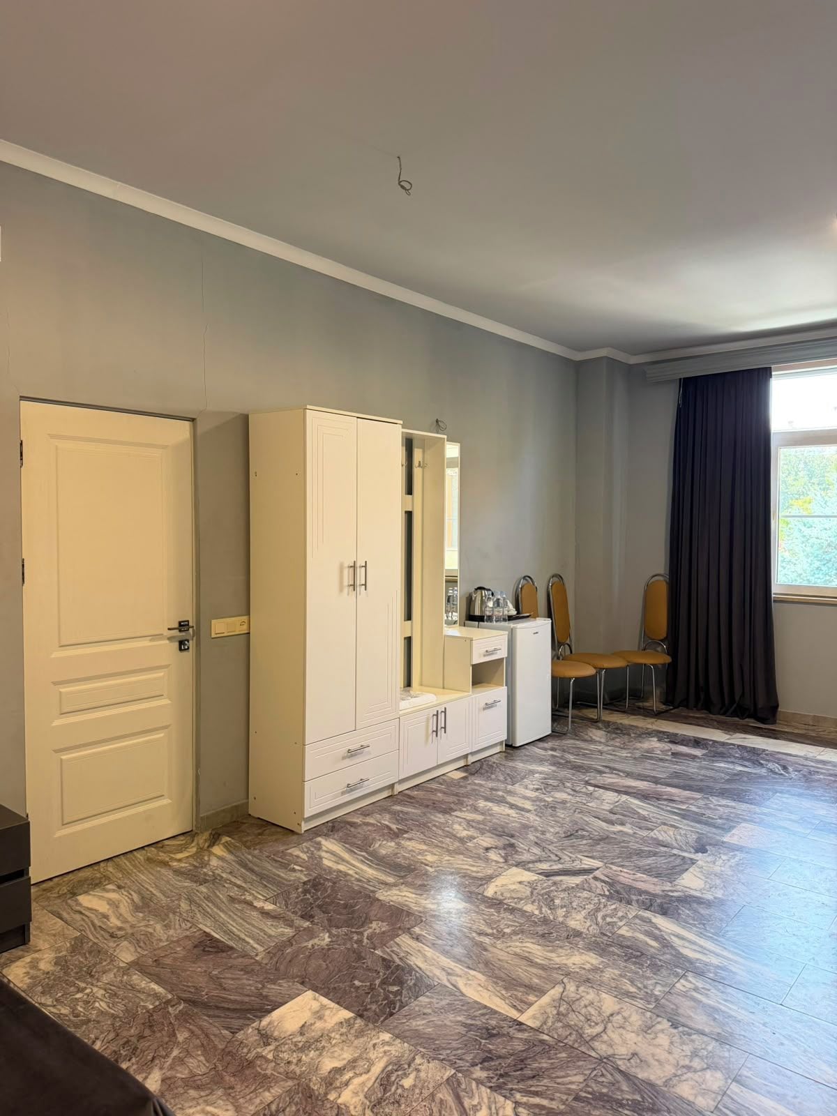 Quarto com guarda-roupa, uma mesinha e uma cadeira.