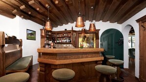 Uma área de bar com mobiliário de madeira, luminárias pendentes em cobre e um balcão.