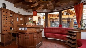 Interior de madeira com um sofá vermelho, um armário de madeira e uma janela com vista para um edifício.