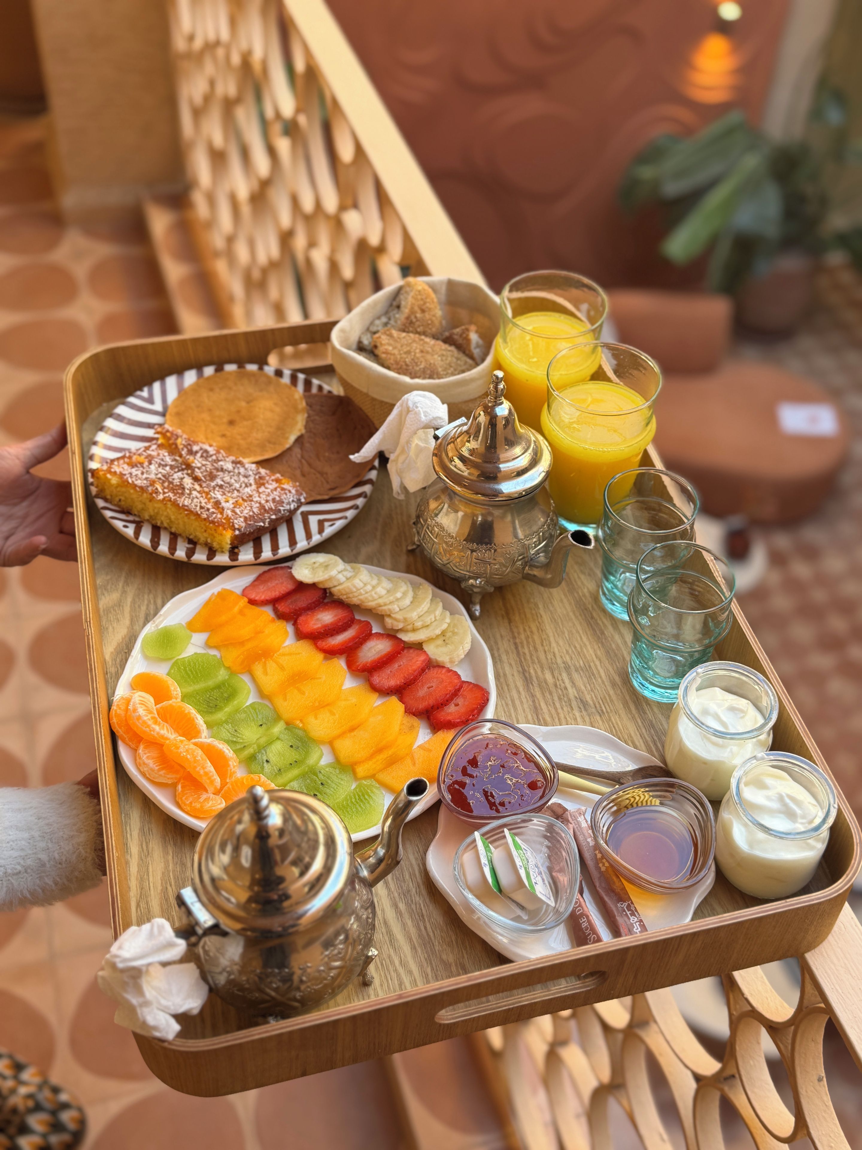 Uma bandeja com itens de café da manhã, incluindo pães, frutas e bebidas.