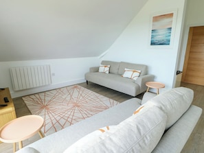 Uma sala de estar moderna com um sofá, uma mesinha redonda, um radiador e um quadro na parede.