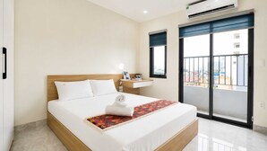 Quarto de hotel com cama, mesa de cabeceira, janela e ar condicionado.