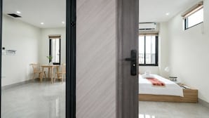 Quarto de hotel moderno com cama, escrivaninha e cadeira, com vista para o exterior.