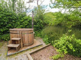 Estrutura de sauna de madeira ao ar livre com banco, rodeada por vegetação densa.
