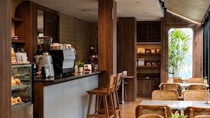 Um café com balcão, banquetes altos e uma área de estar com mesas e cadeiras.